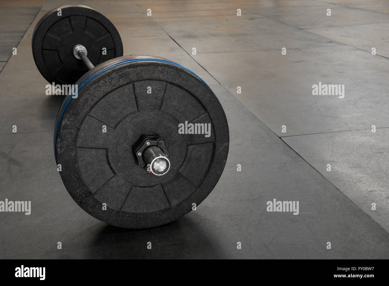 Barbell with black and blue plates on a gym floor Stock Photo - Alamy