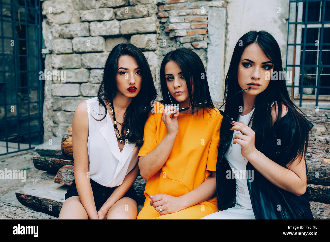 Three young beautiful girls posing against the backdrop of an abandoned ...