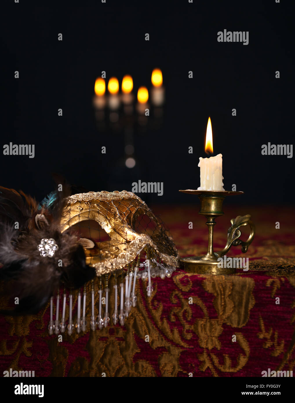 Candle in small brass candlestick and Venetian mask Stock Photo - Alamy