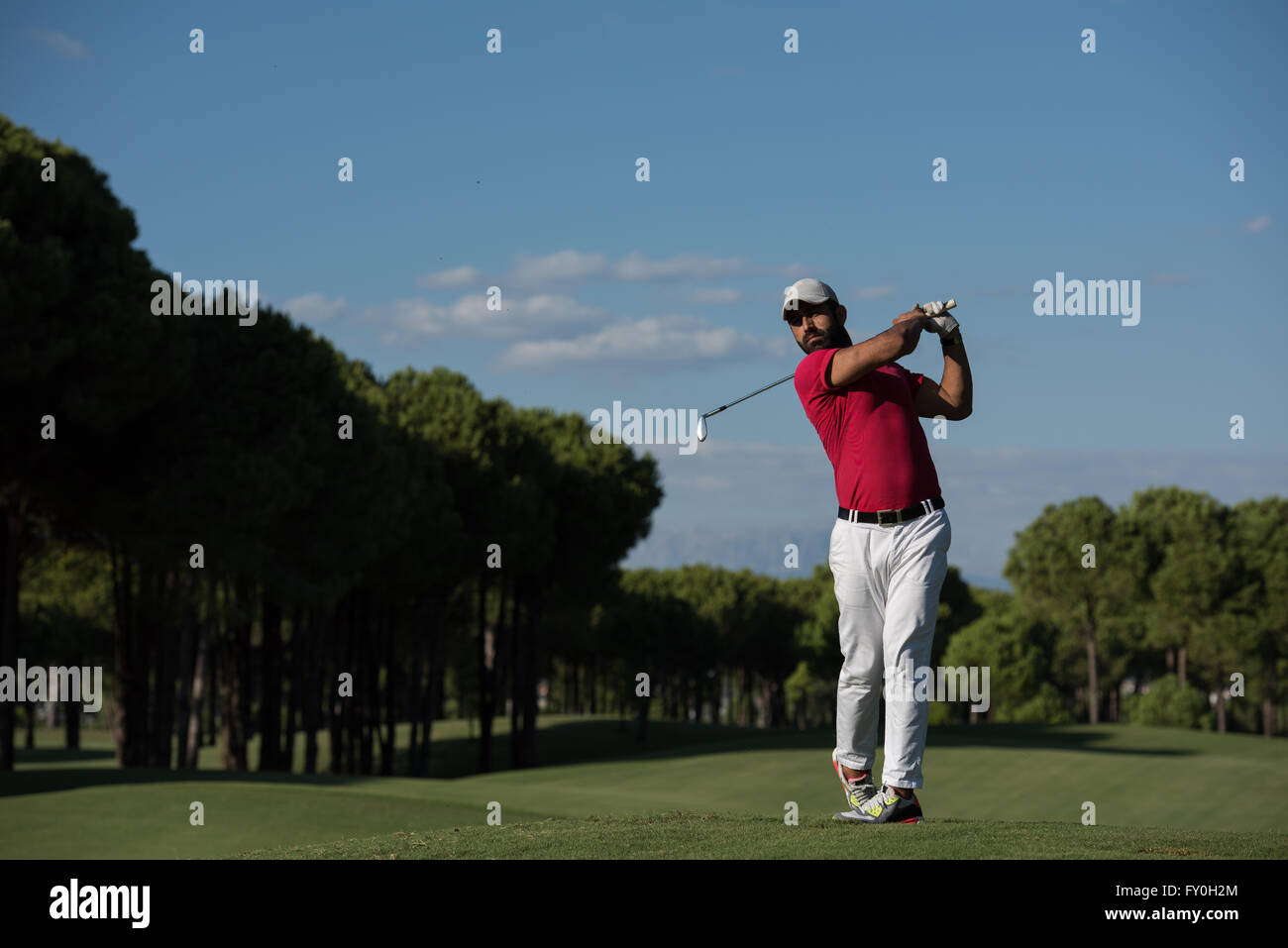 golf player hitting shot with driver on course at beautiful sunny day ...