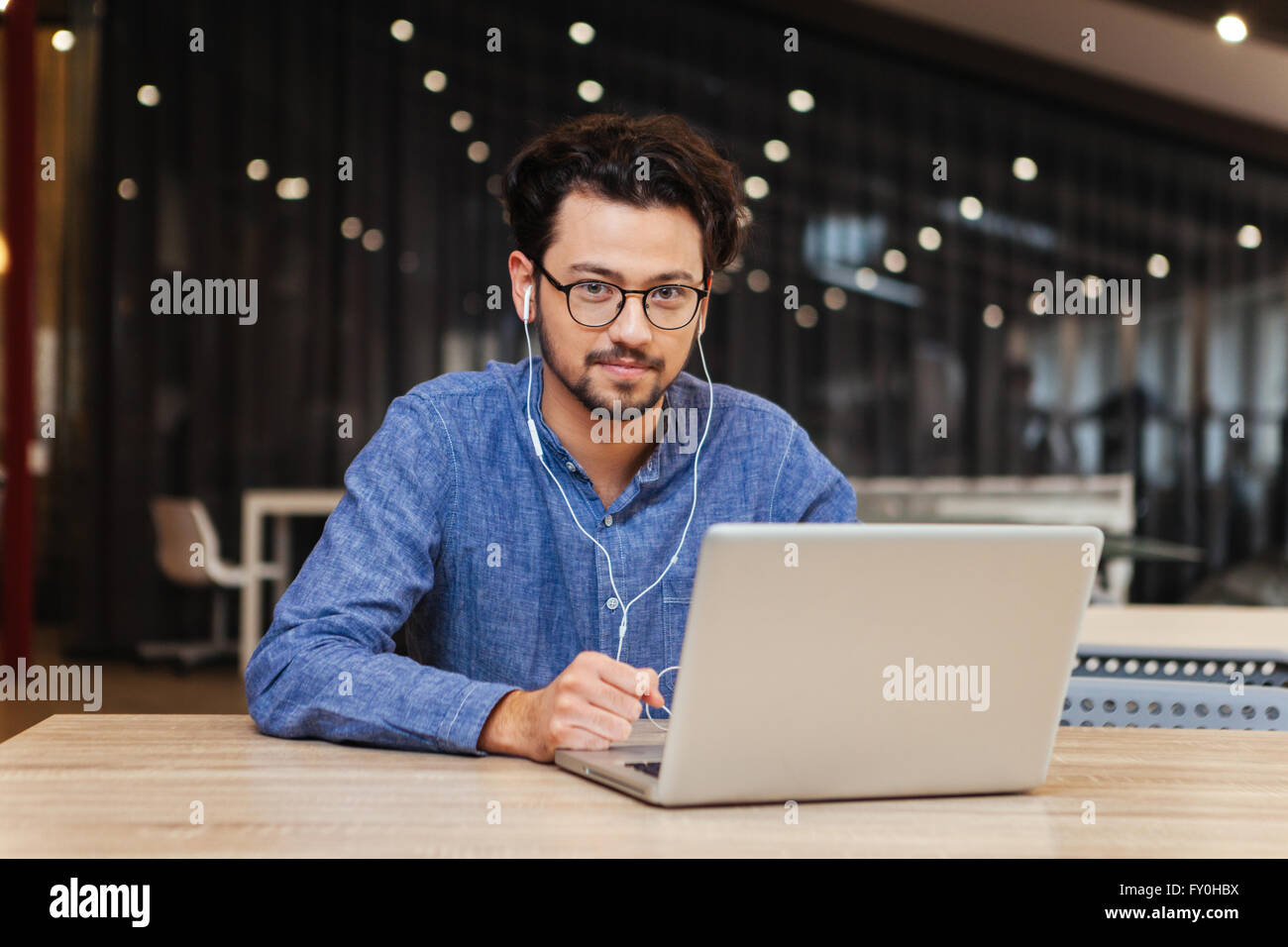 Handsome man in casual cloth sitting at the table with laptop computer ...