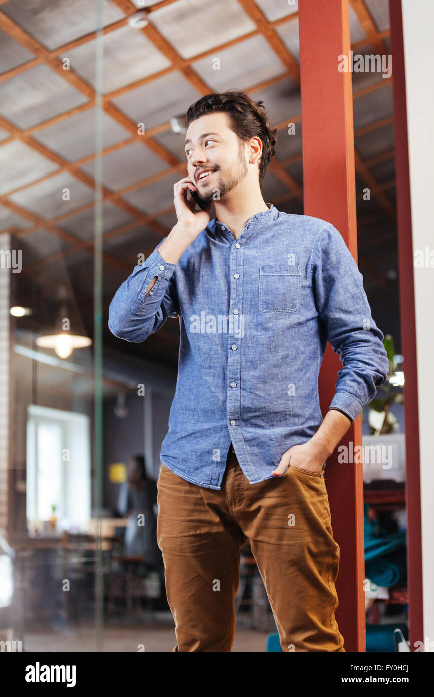 Happy casual man speaking on the phone in office Stock Photo - Alamy
