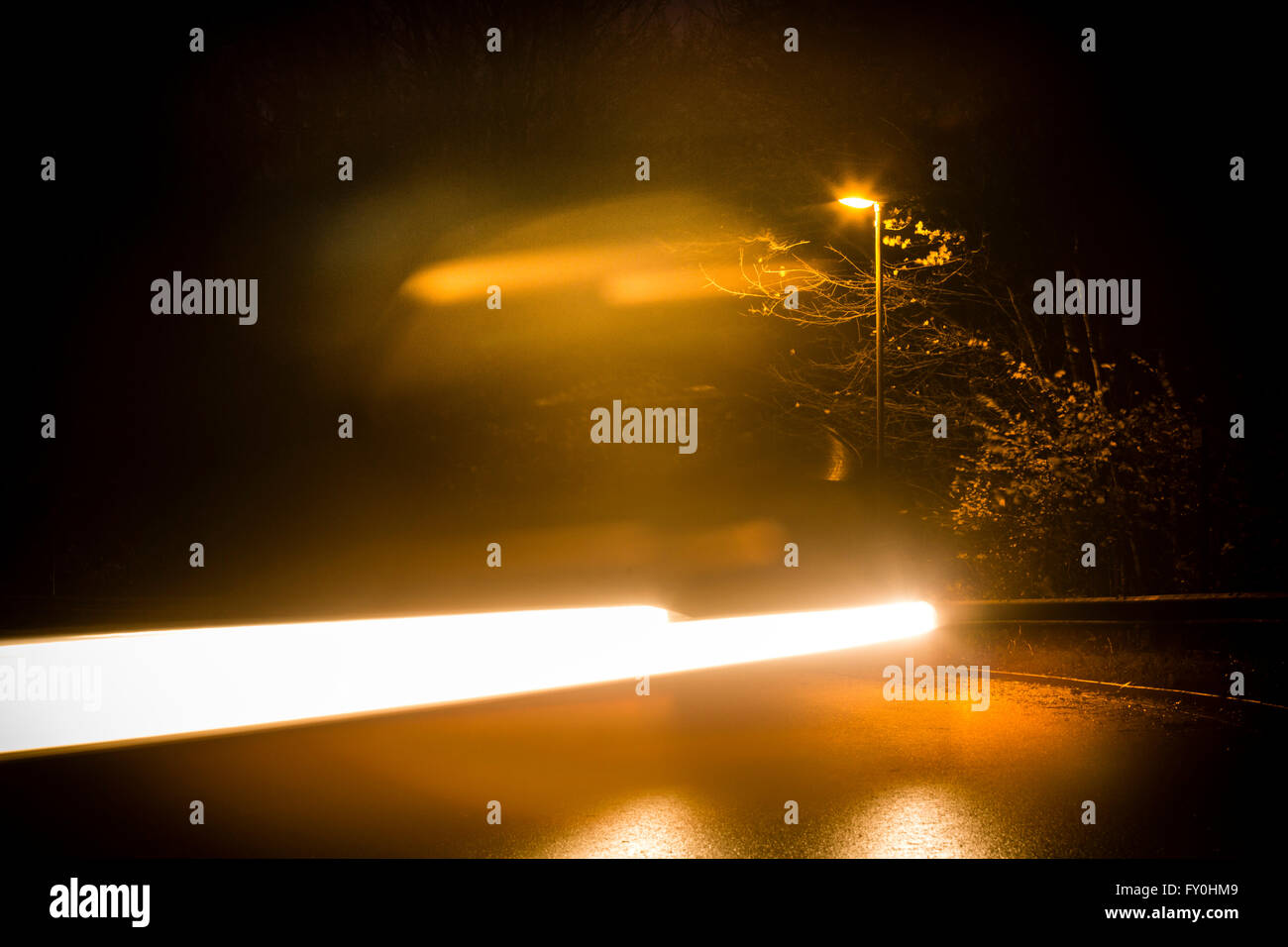 Night time road scene with street lamps, car light trails and ...