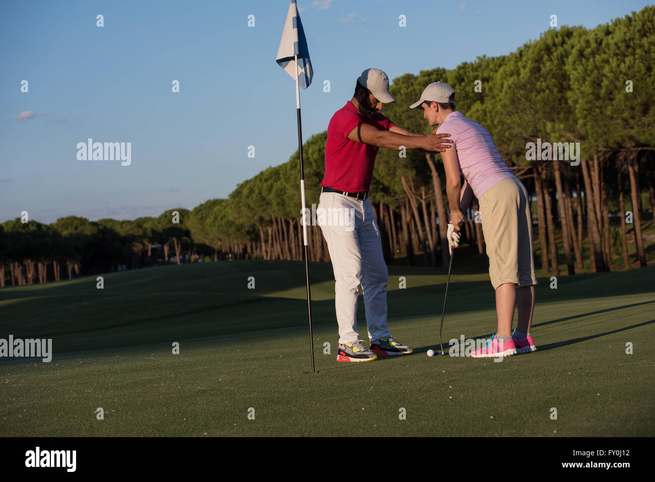 male golf instructor teaching female golf player, personal trainer ...