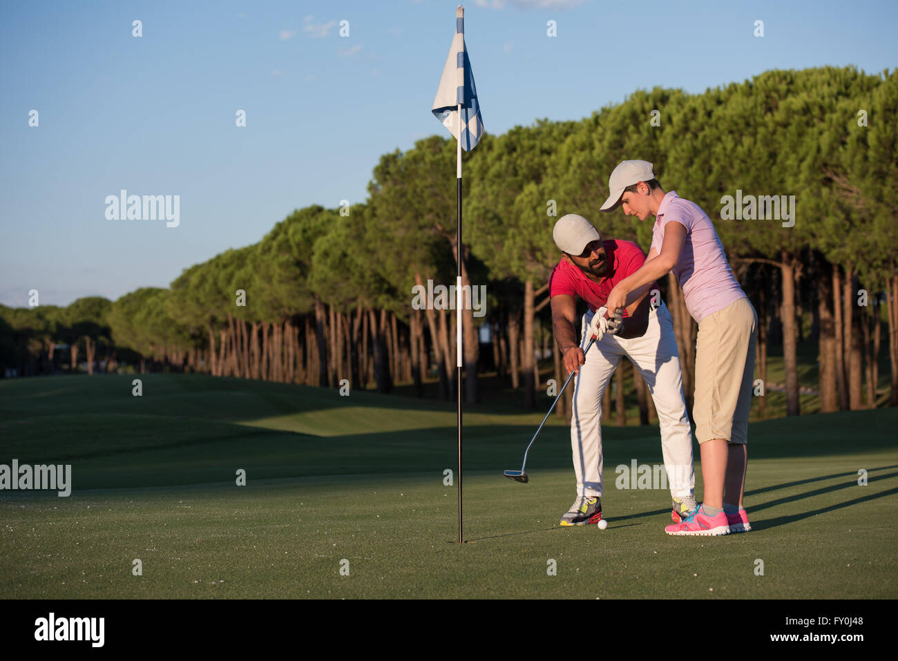 male golf instructor teaching female golf player, personal trainer ...