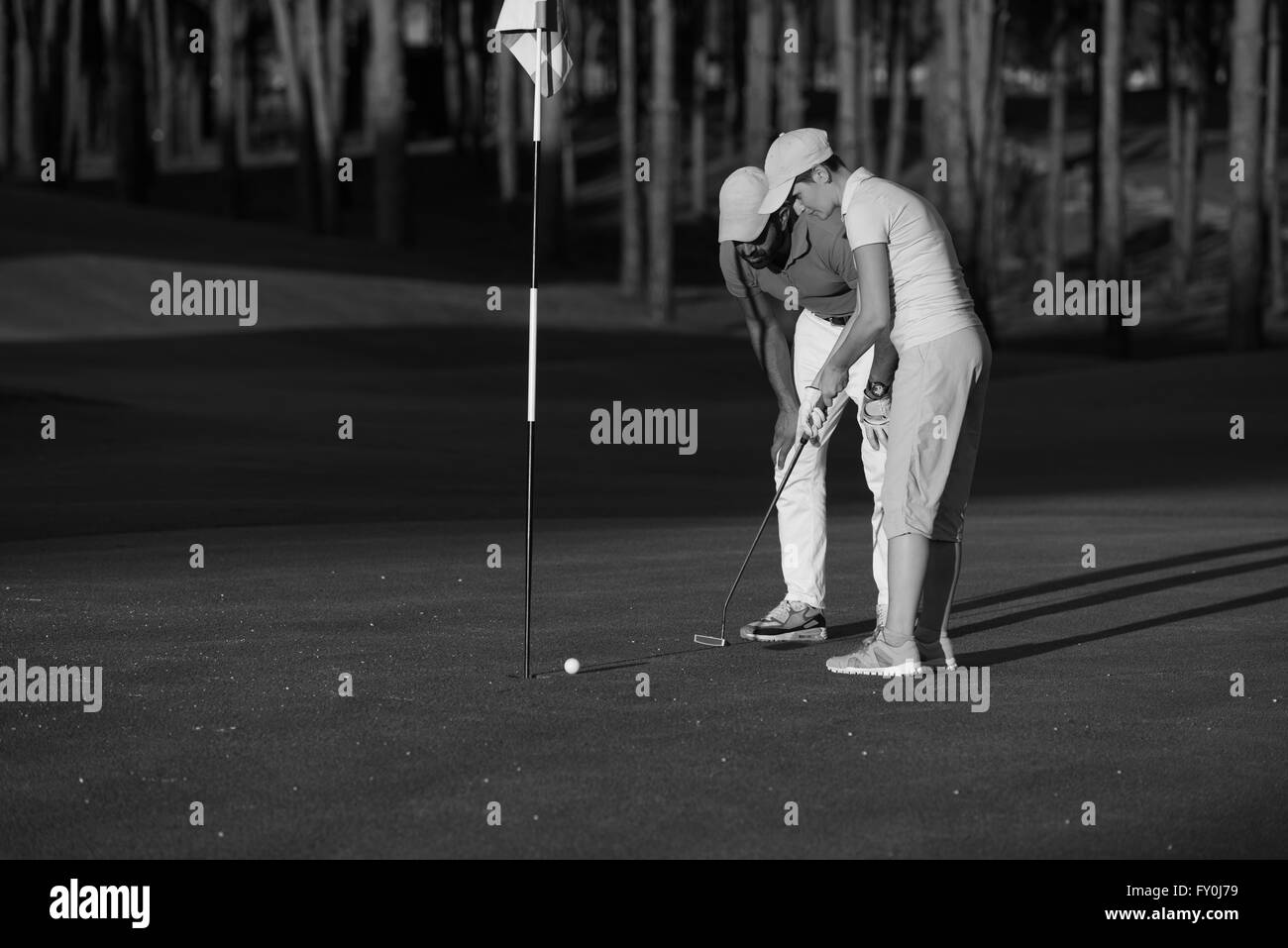 male golf instructor teaching female golf player, personal trainer ...