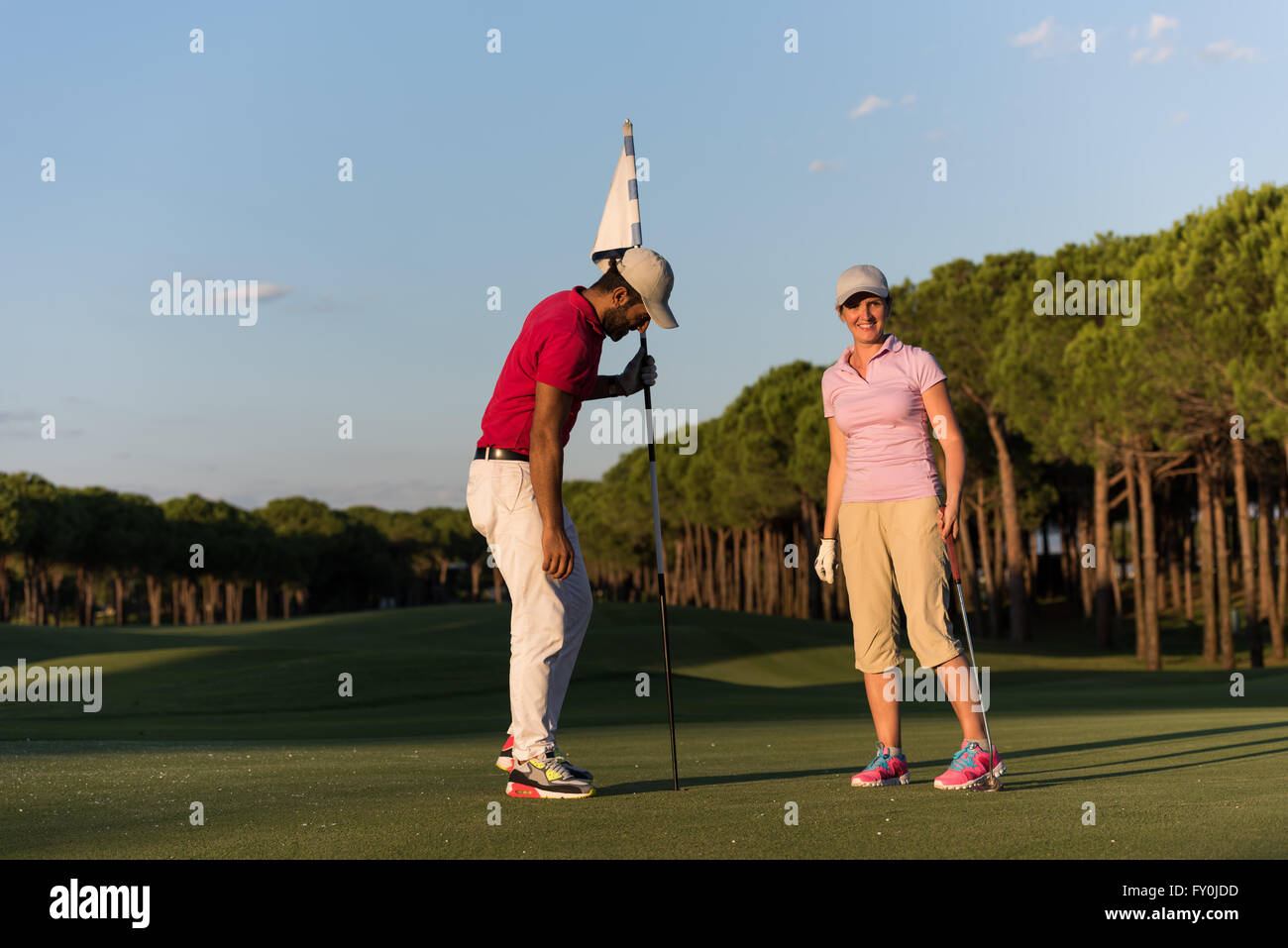 male golf instructor teaching female golf player, personal trainer ...