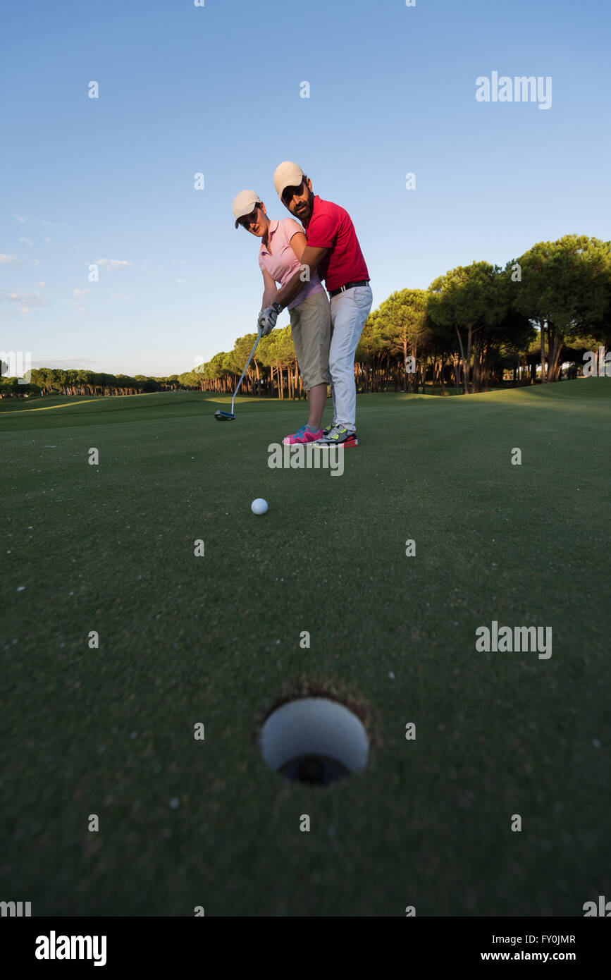 male golf instructor teaching female golf player, personal trainer ...