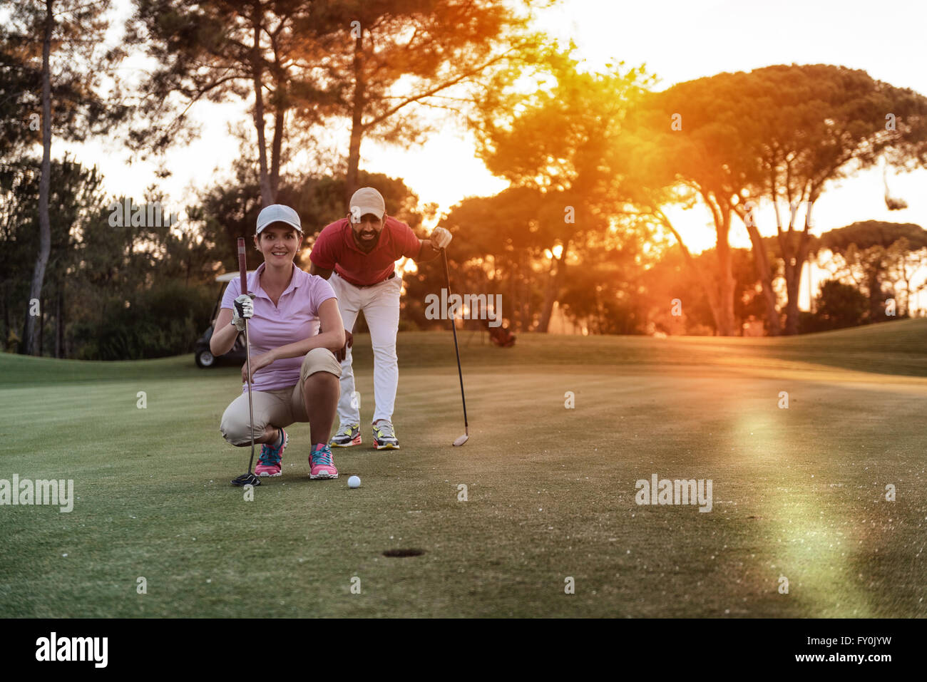 portrait of happy young couple on golf course with beautiful sunset in ...