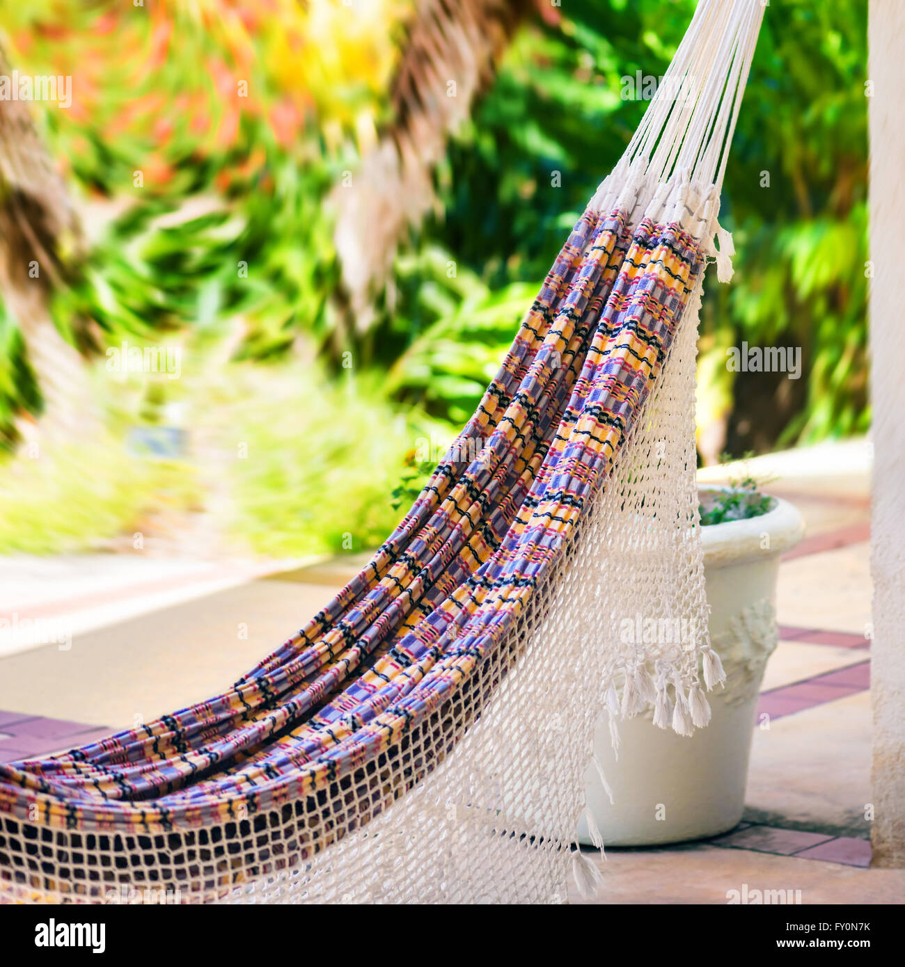 Empty colorful cloth and rope hammock hanging by the garden patio ...