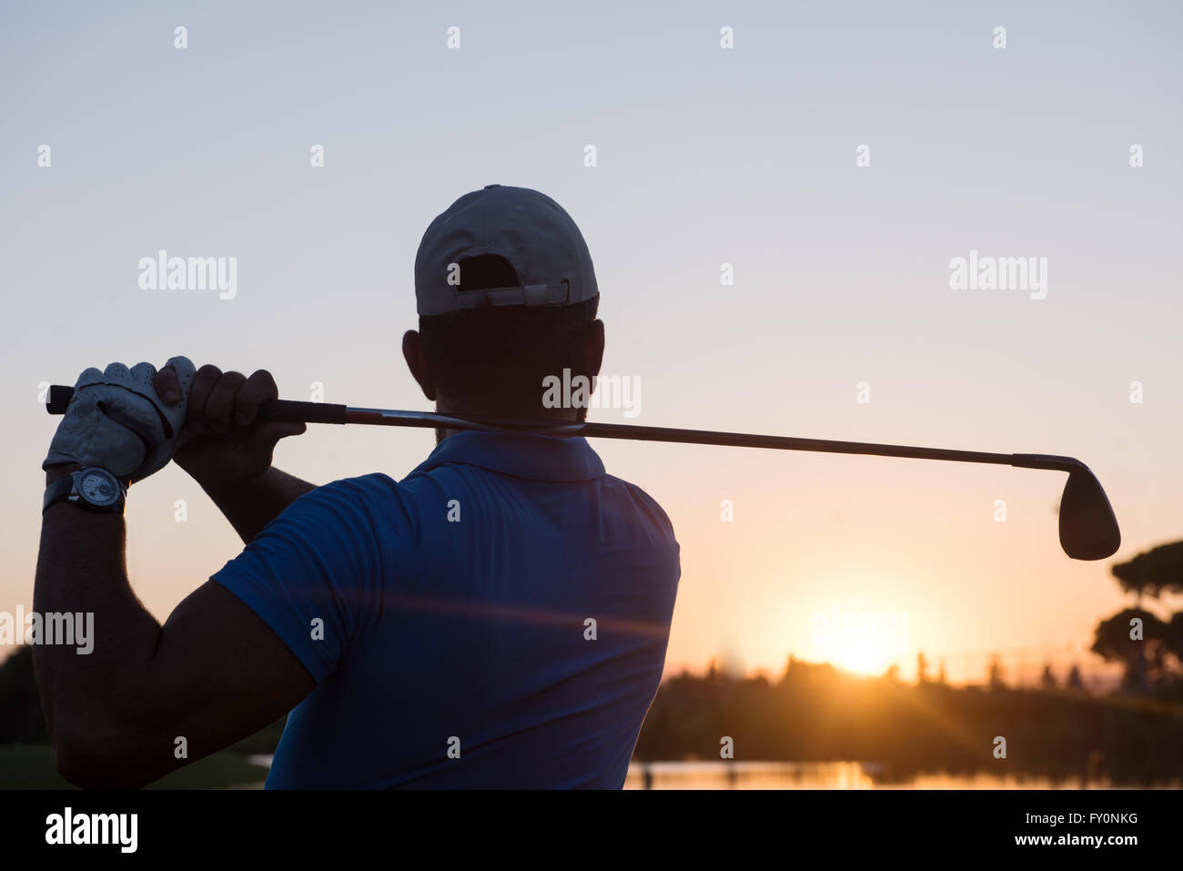 golfer hitting long shot with driver on course at beautiful sunset ...