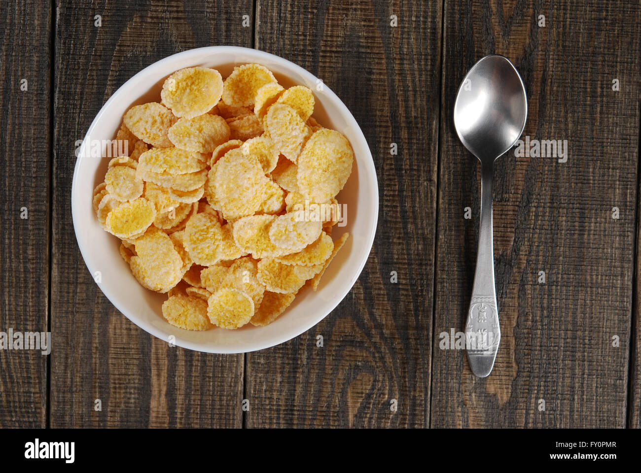 Corn flakes in small white bowls with a spoon on a dark wooden ...
