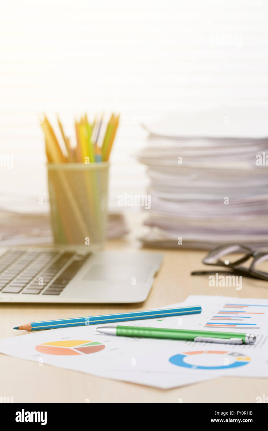 Office workplace with laptop, reports and pencils on wooden desk table ...