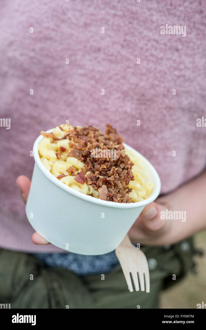 Hand holding mac and cheese in a white take away bowl Stock Photo - Alamy