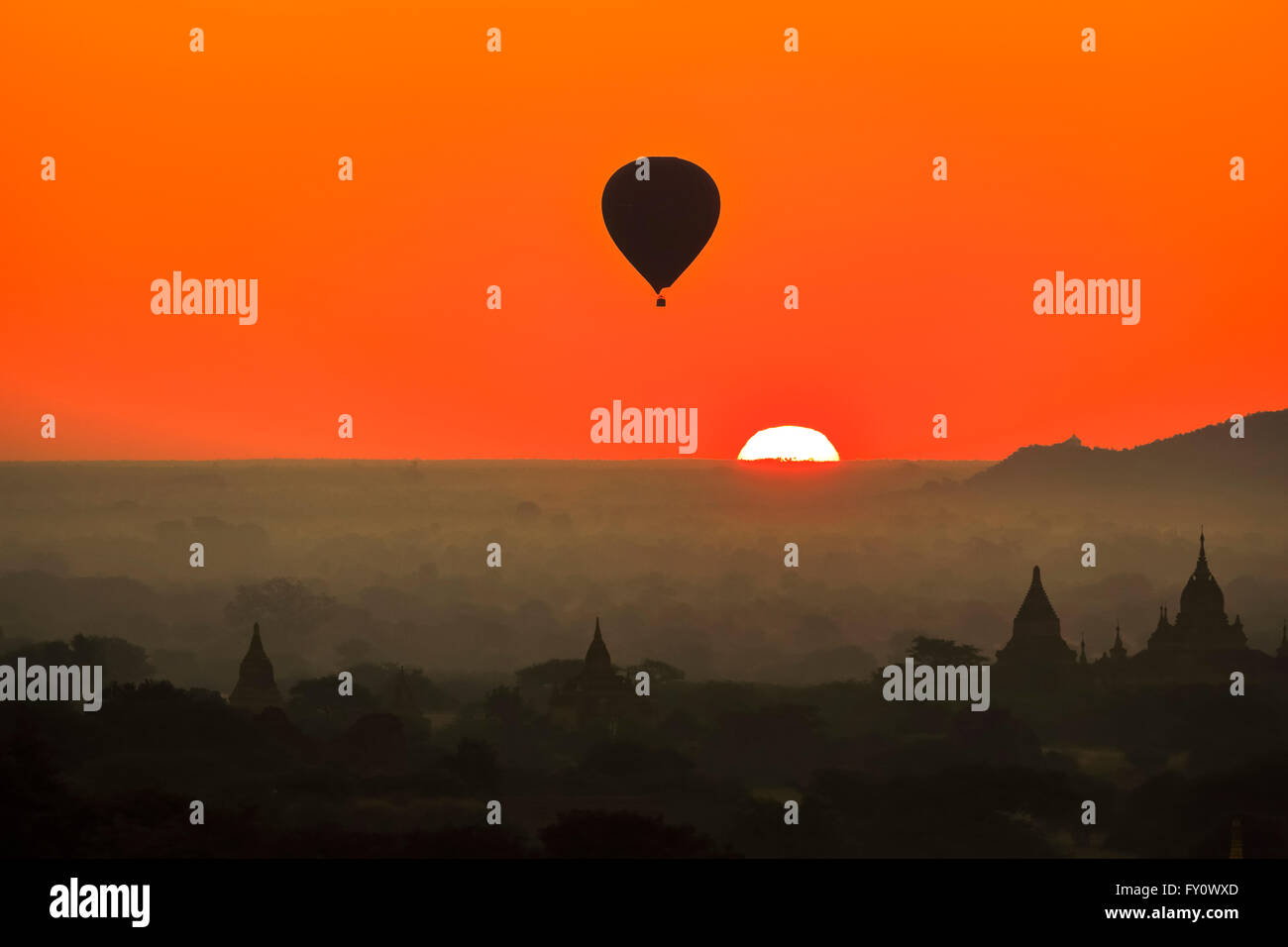 Sun rising over the horizon and hot air balloon flying at Old Bagan ...