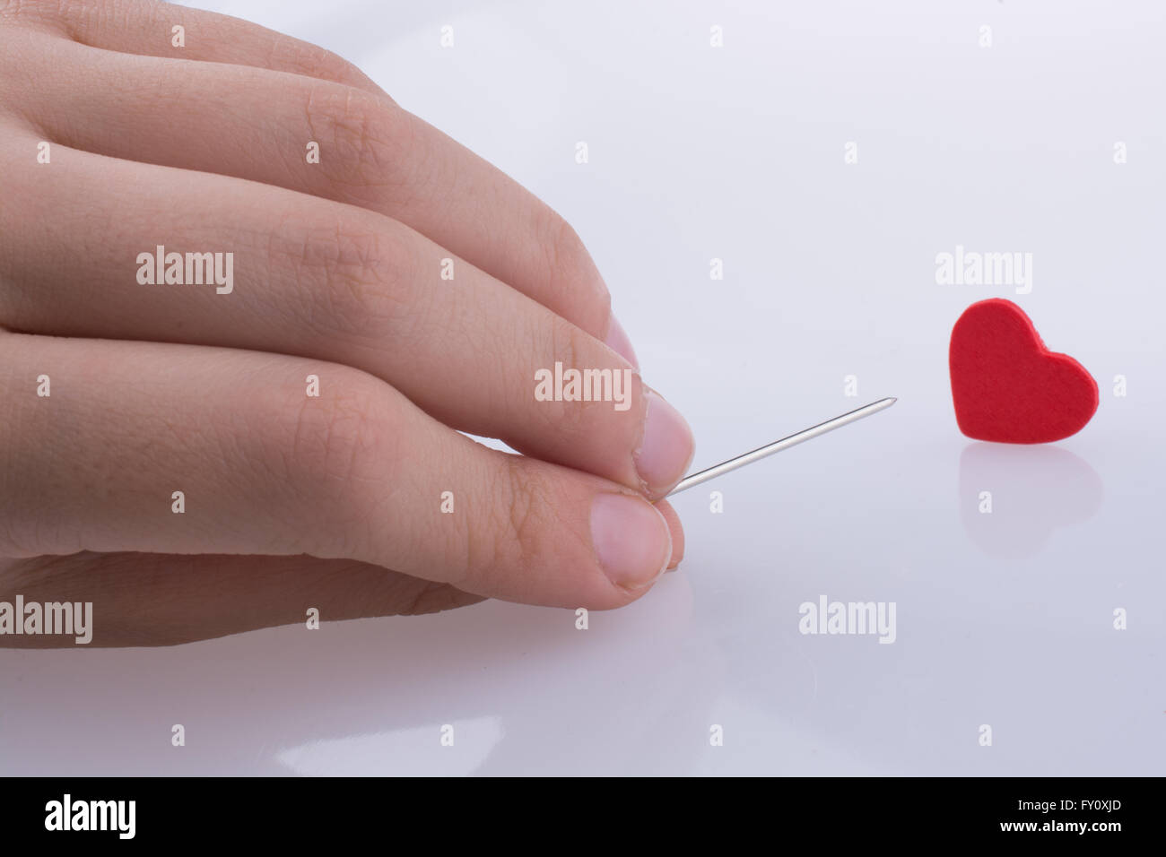 Hand pointing a needle on a heart Stock Photo - Alamy