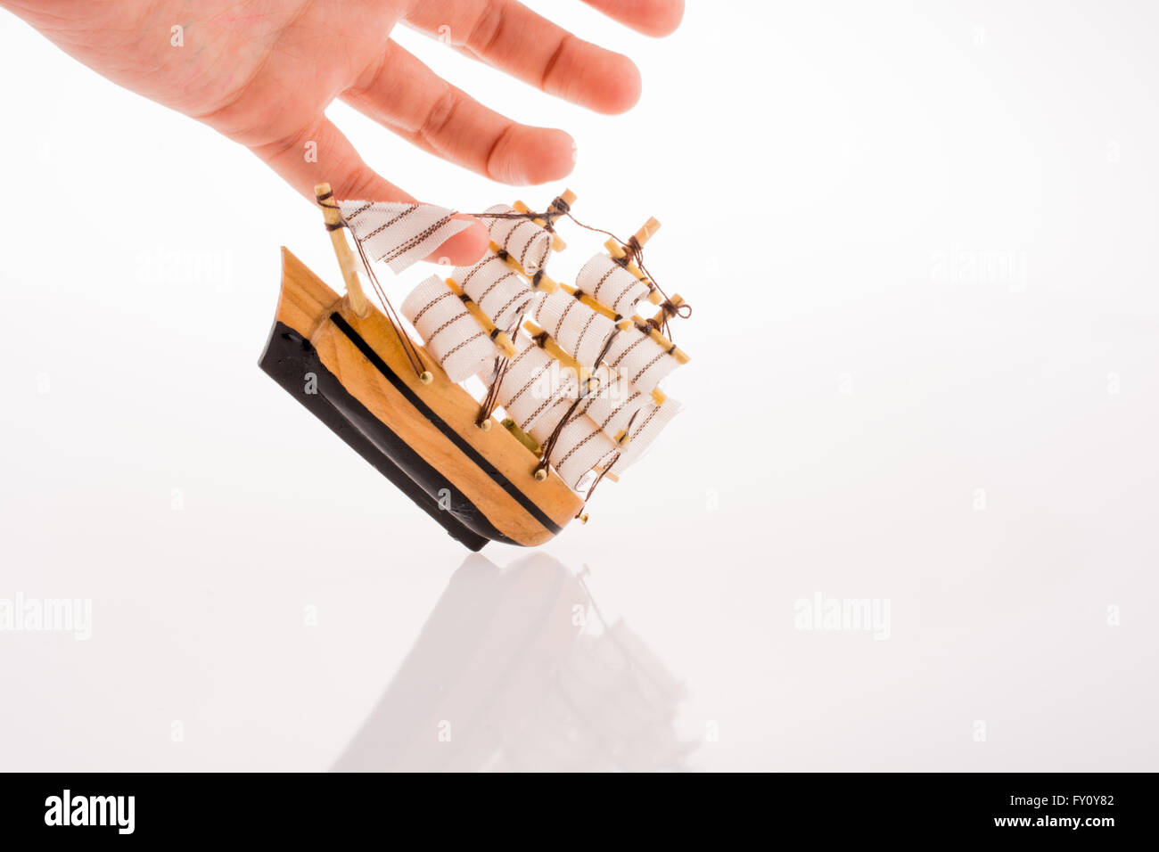 Hand in touch with a little model sailboat on a white background Stock ...