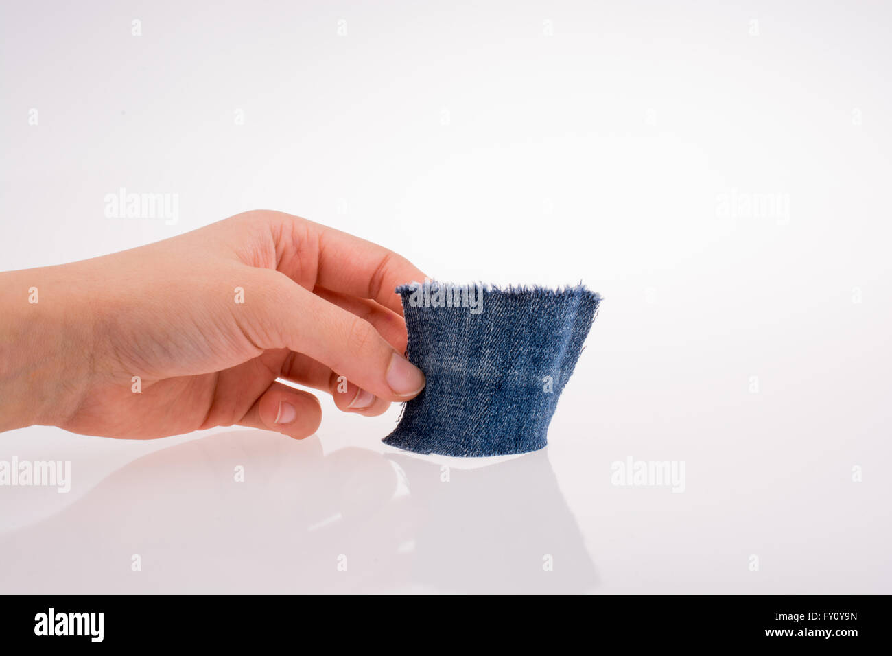 Hand holding a denim fabric piece on white background Stock Photo - Alamy
