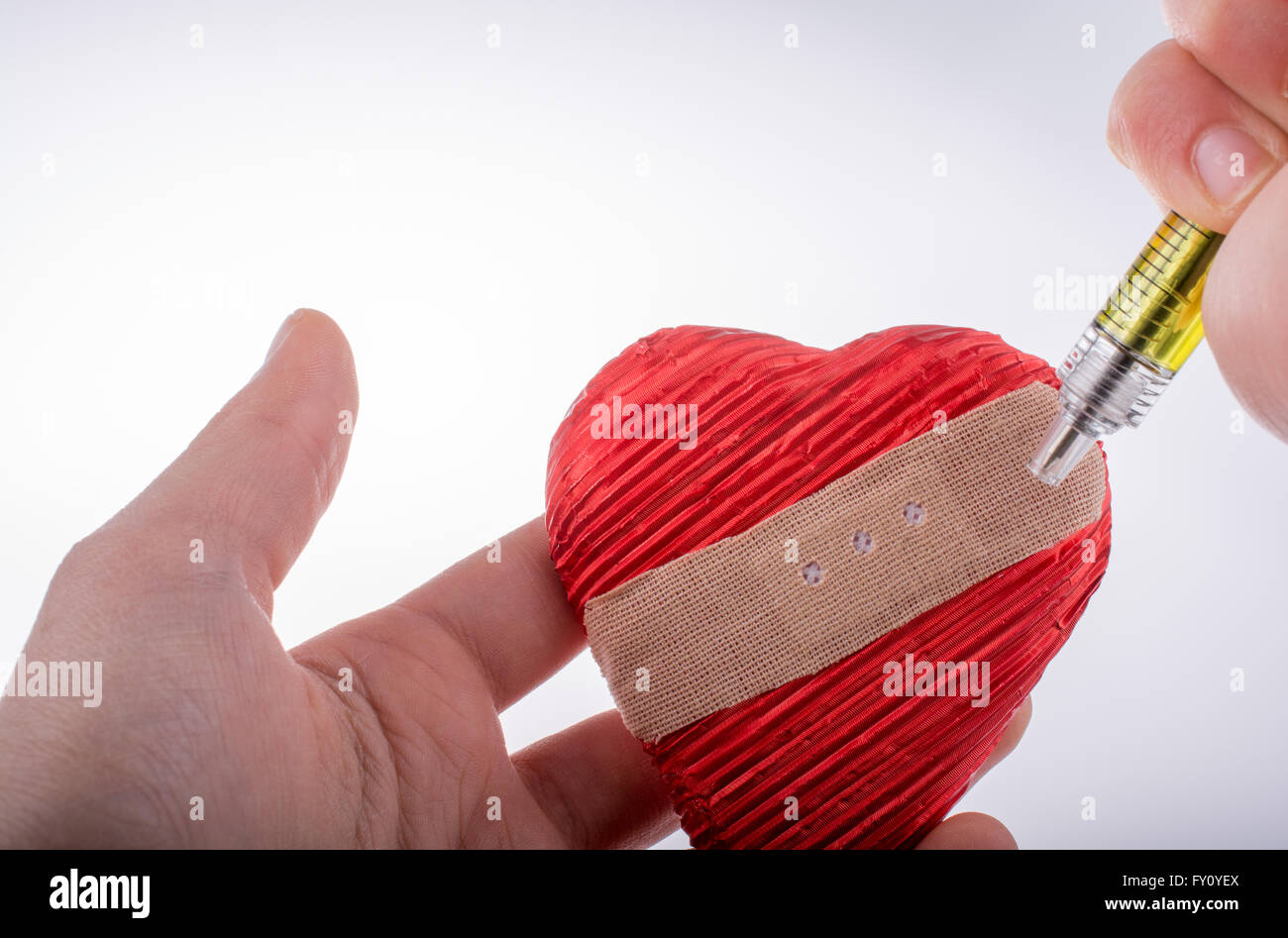 Hand injecting love into heart in plaster on white background Stock ...