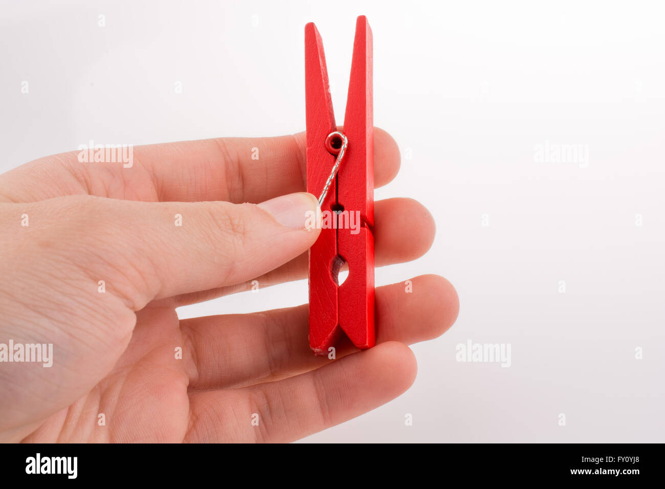 Hand holding a red clothespin on a white background Stock Photo - Alamy