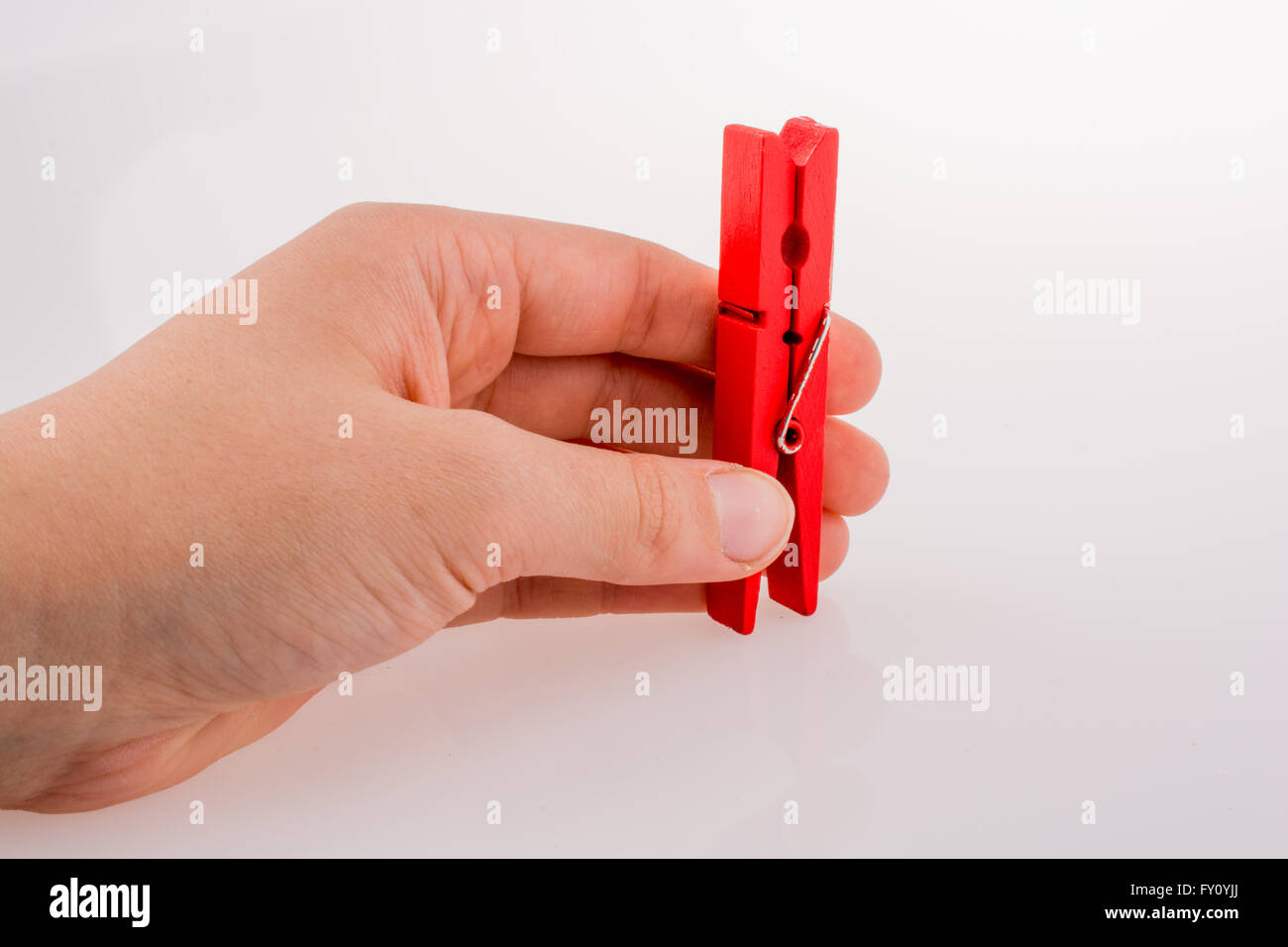 Hand holding a red clothespin on a white background Stock Photo - Alamy