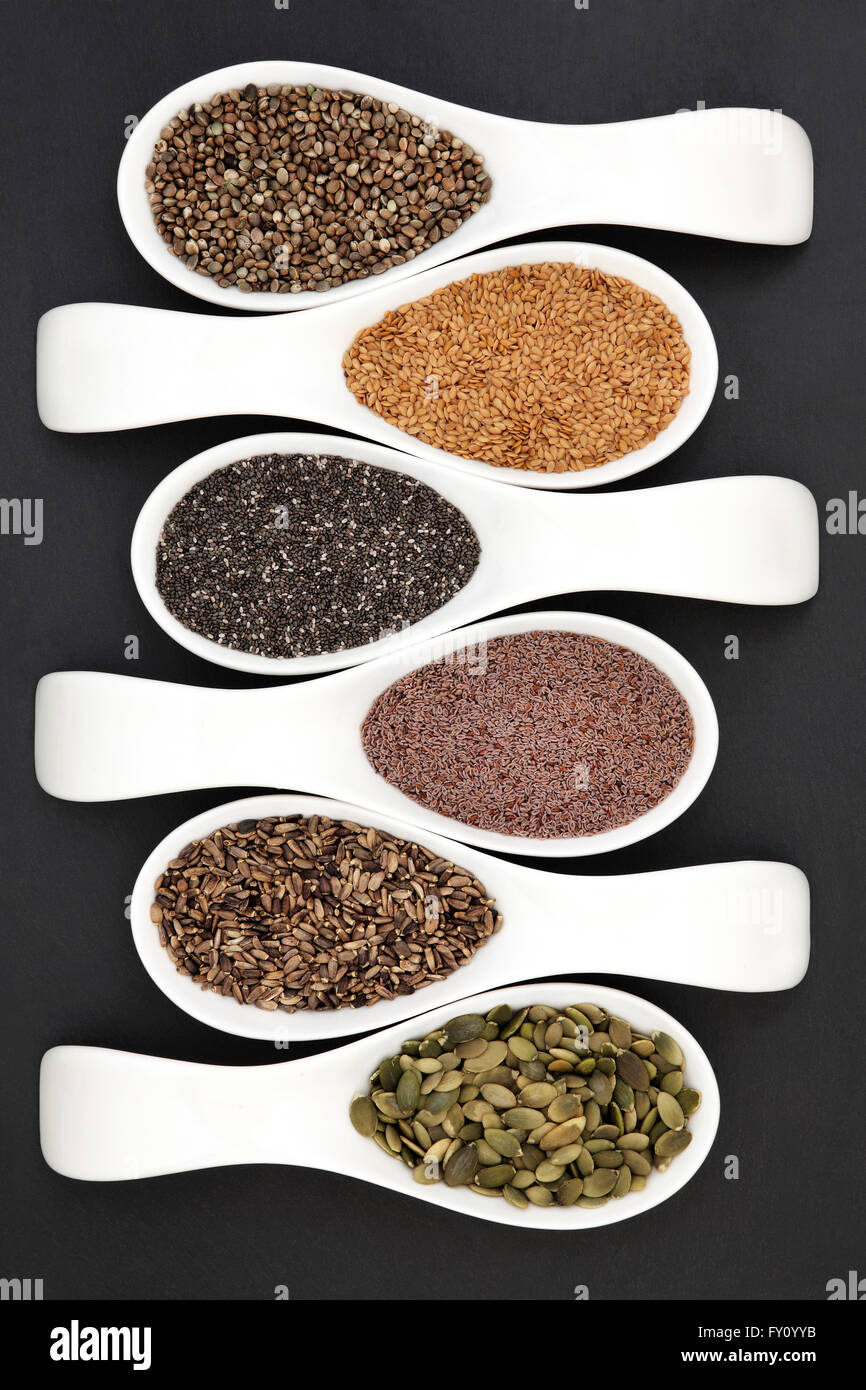 Healthy seed food selection in white porcelain scoops over grey slate ...
