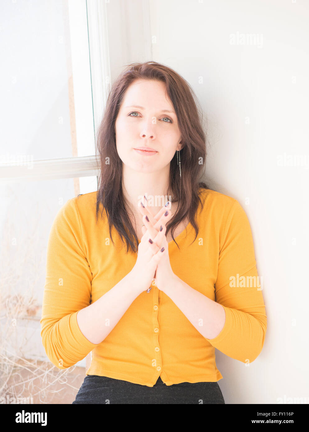 Woman sitting by window, looking at camera. Lifestyle image showing a ...