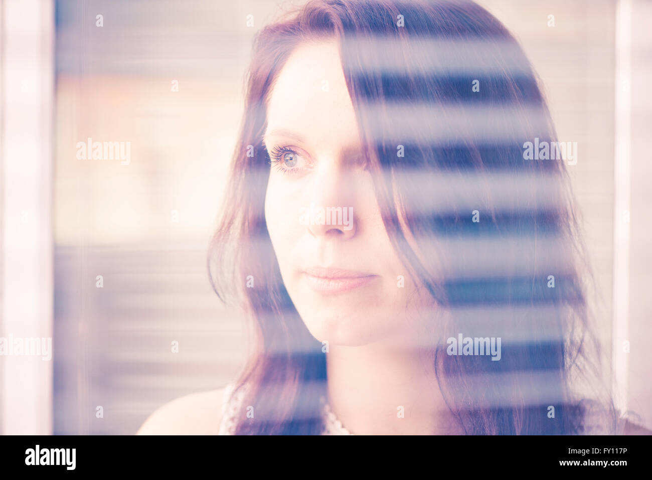 Woman standing by a window, looking away. Concept of sadness, waiting ...
