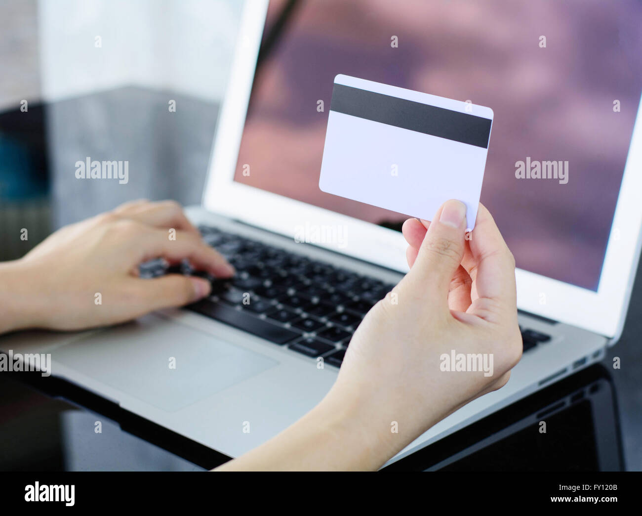 woman holding credit card in hand and entering information into a ...