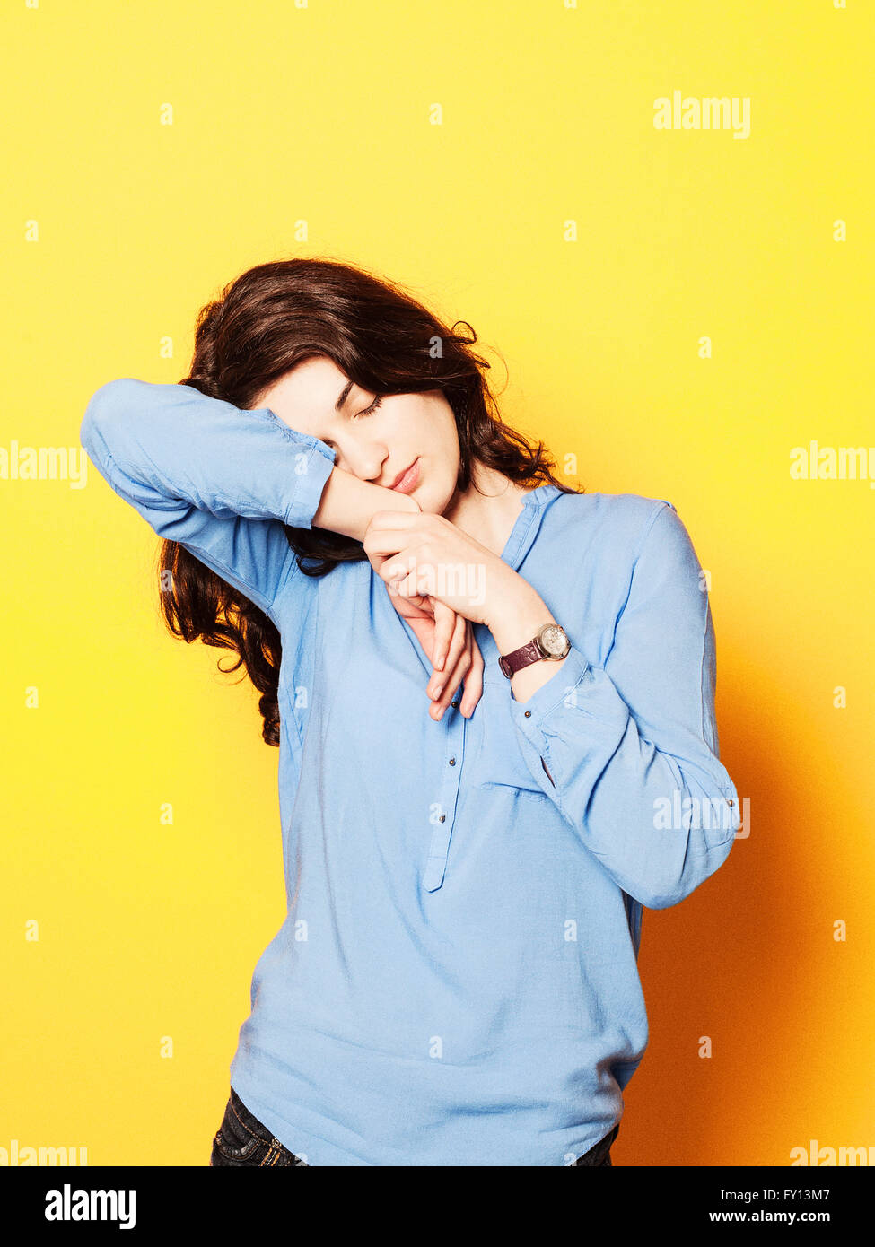 Tired young woman sleeping on hand against yellow background Stock ...