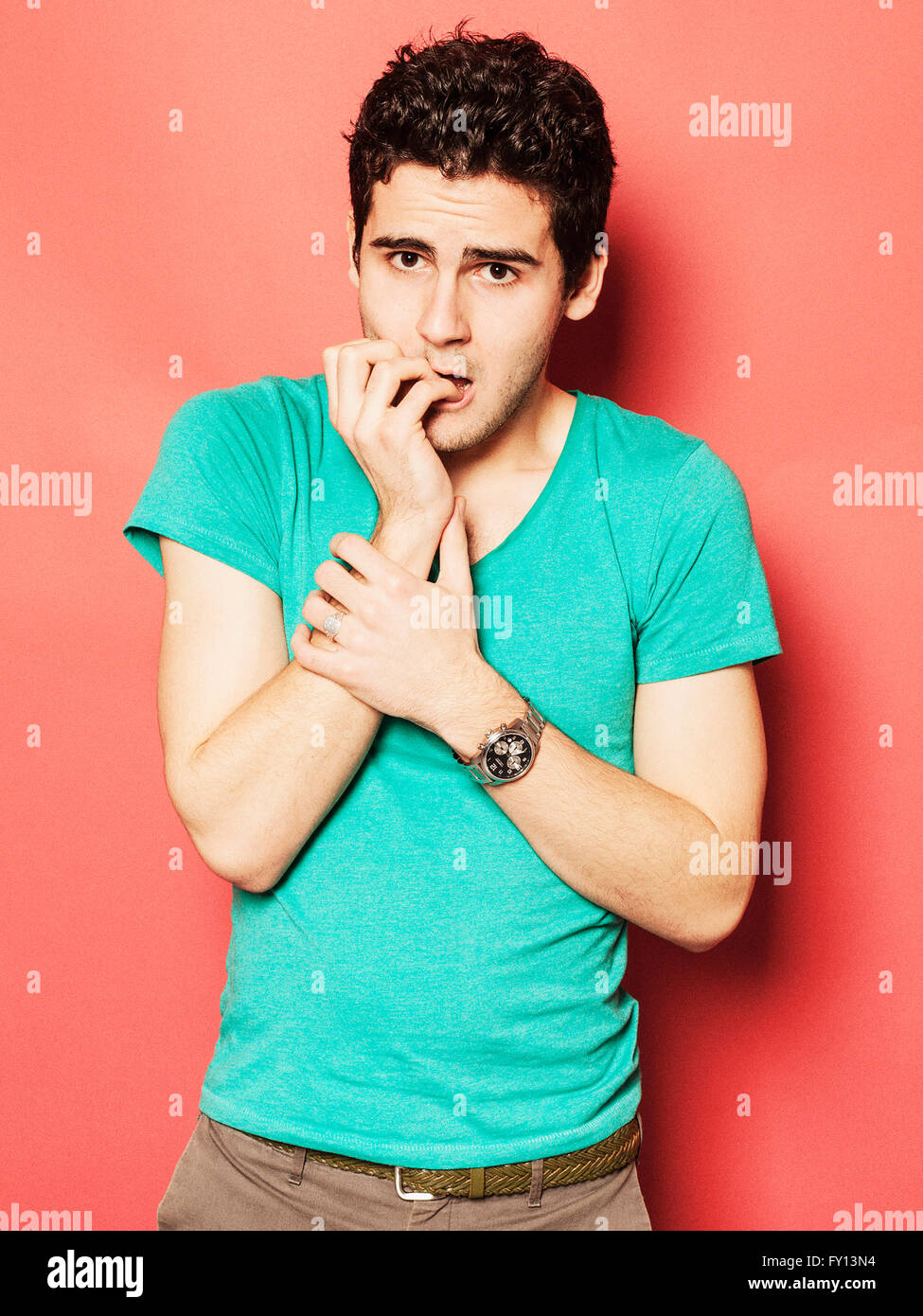 Portrait of nervous young man biting nails against red background Stock ...
