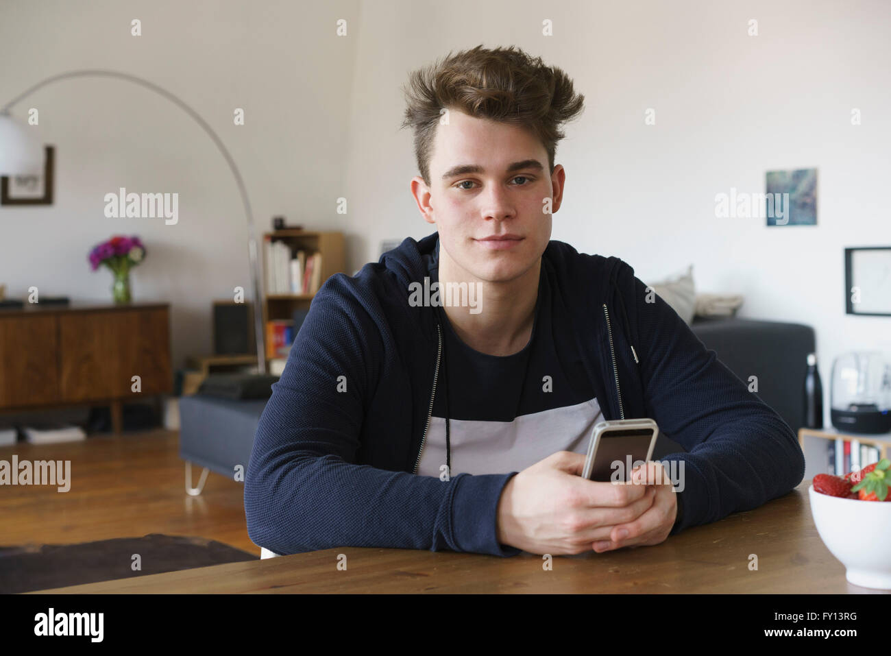 Portrait of teenage boy sitting at table with smart phone Stock Photo ...