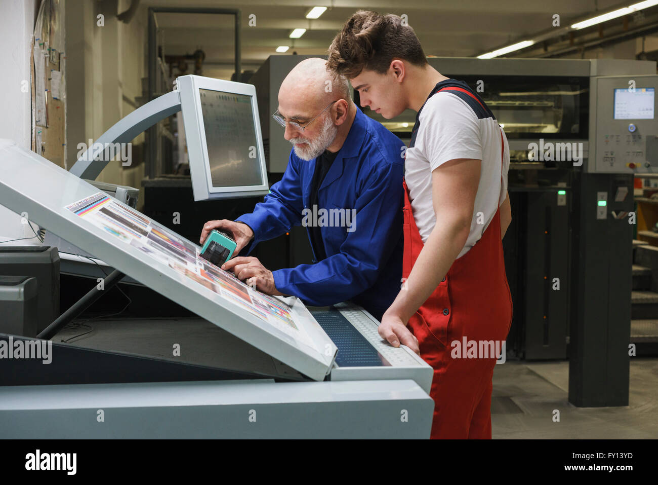 Mature worker showing colleague quality of printout with scanner at ...