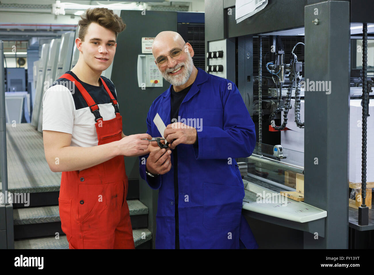 Portrait of workers holding tool and standing at printing press Stock ...