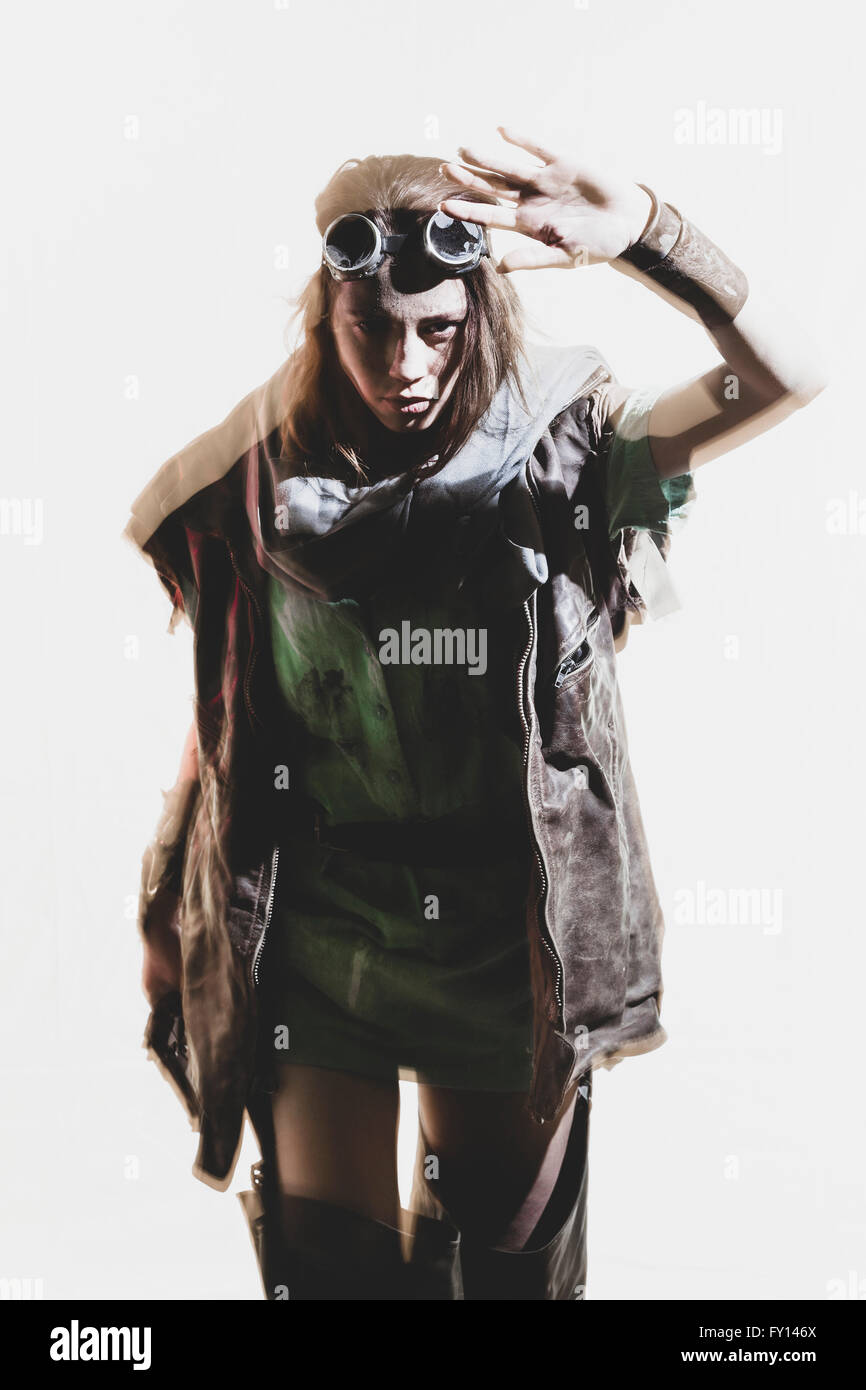 Young woman wearing goggles and jacket gesturing against white ...