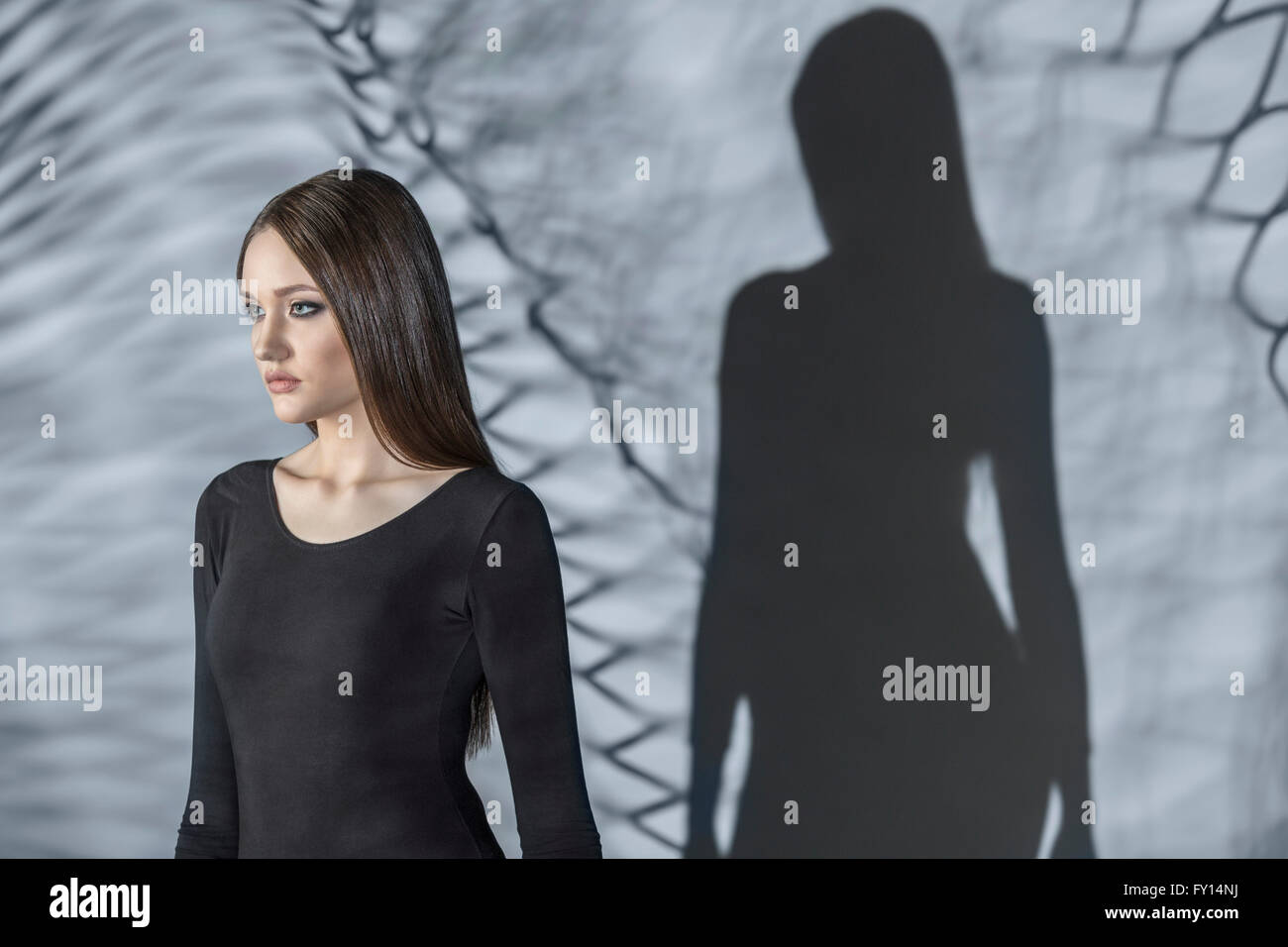 Beautiful woman standing with shadow on gray background Stock Photo - Alamy