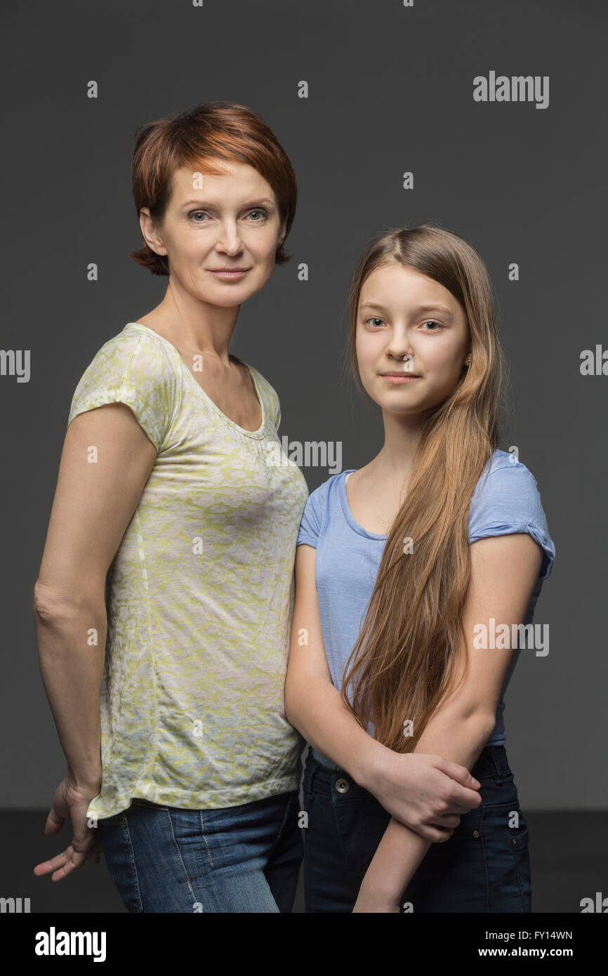 Portrait of mother and daughter standing against gray background Stock ...
