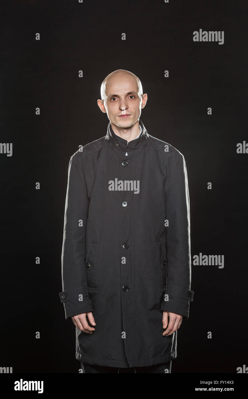 Portrait of serious bald man standing against black background Stock ...