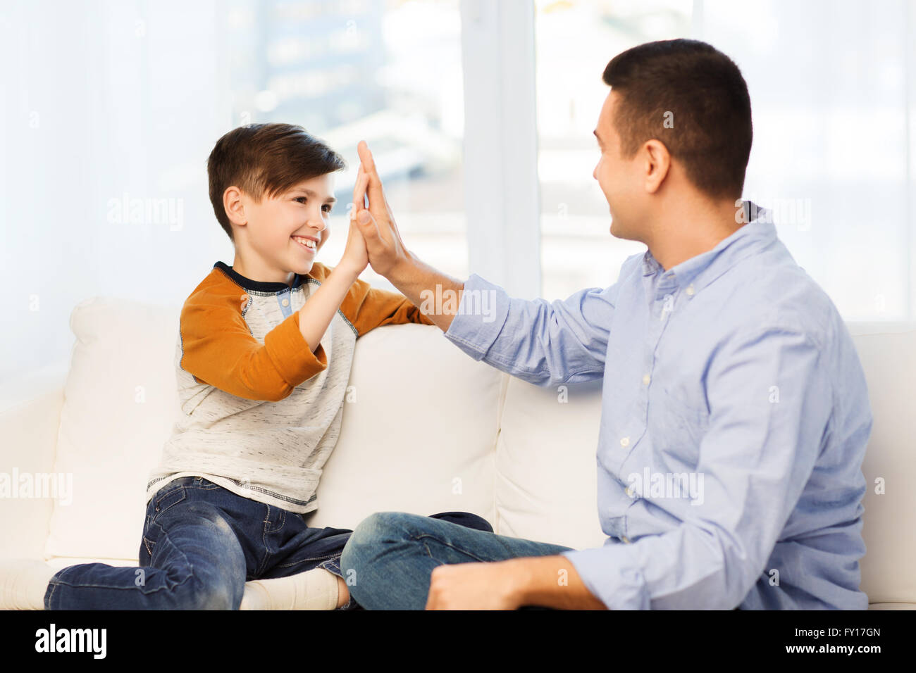 happy father and son doing high five at home Stock Photo - Alamy