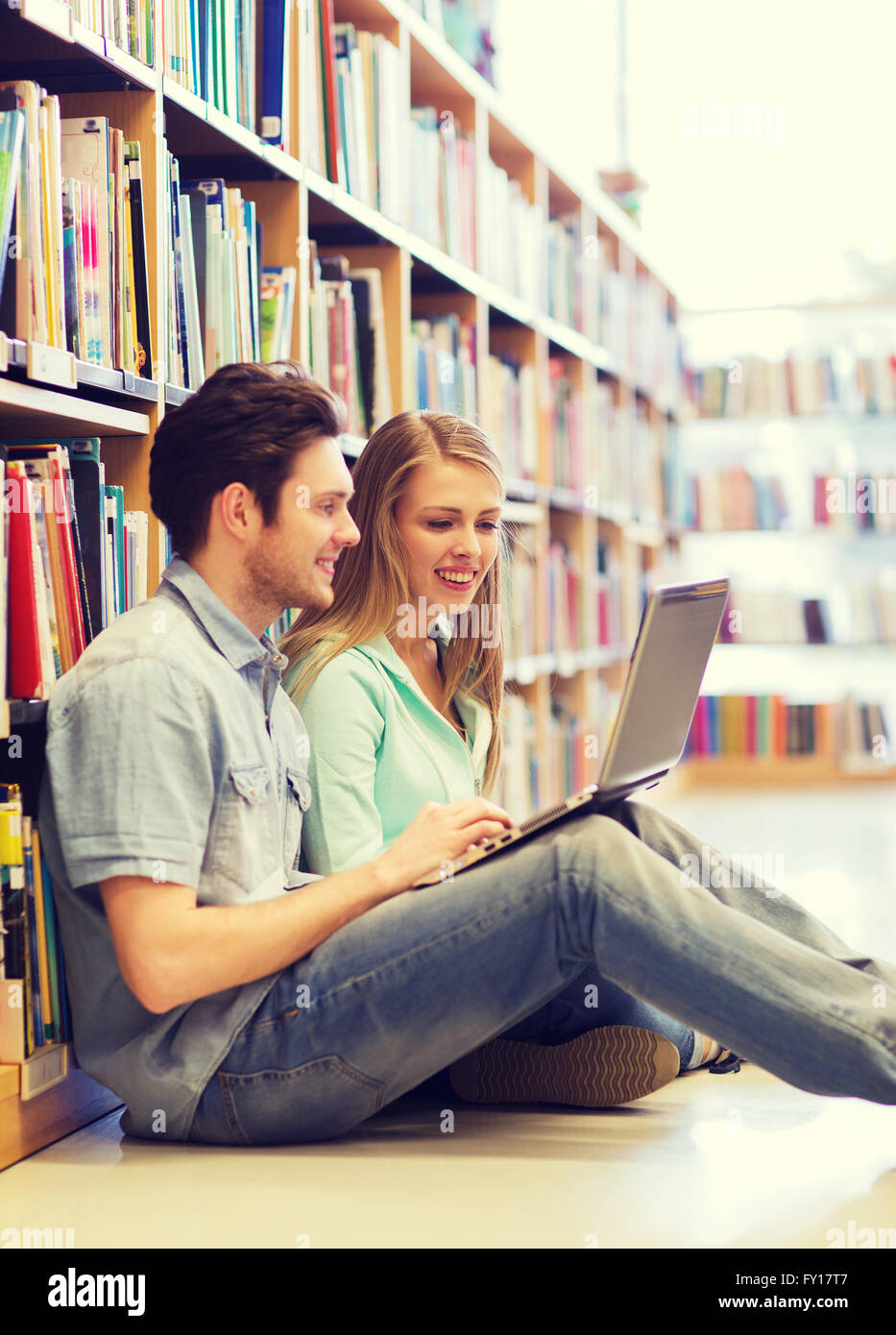 happy students with laptop in library Stock Photo - Alamy