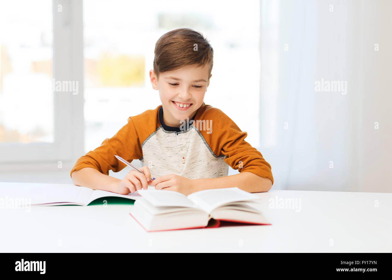 smiling student boy writing to notebook at home Stock Photo - Alamy