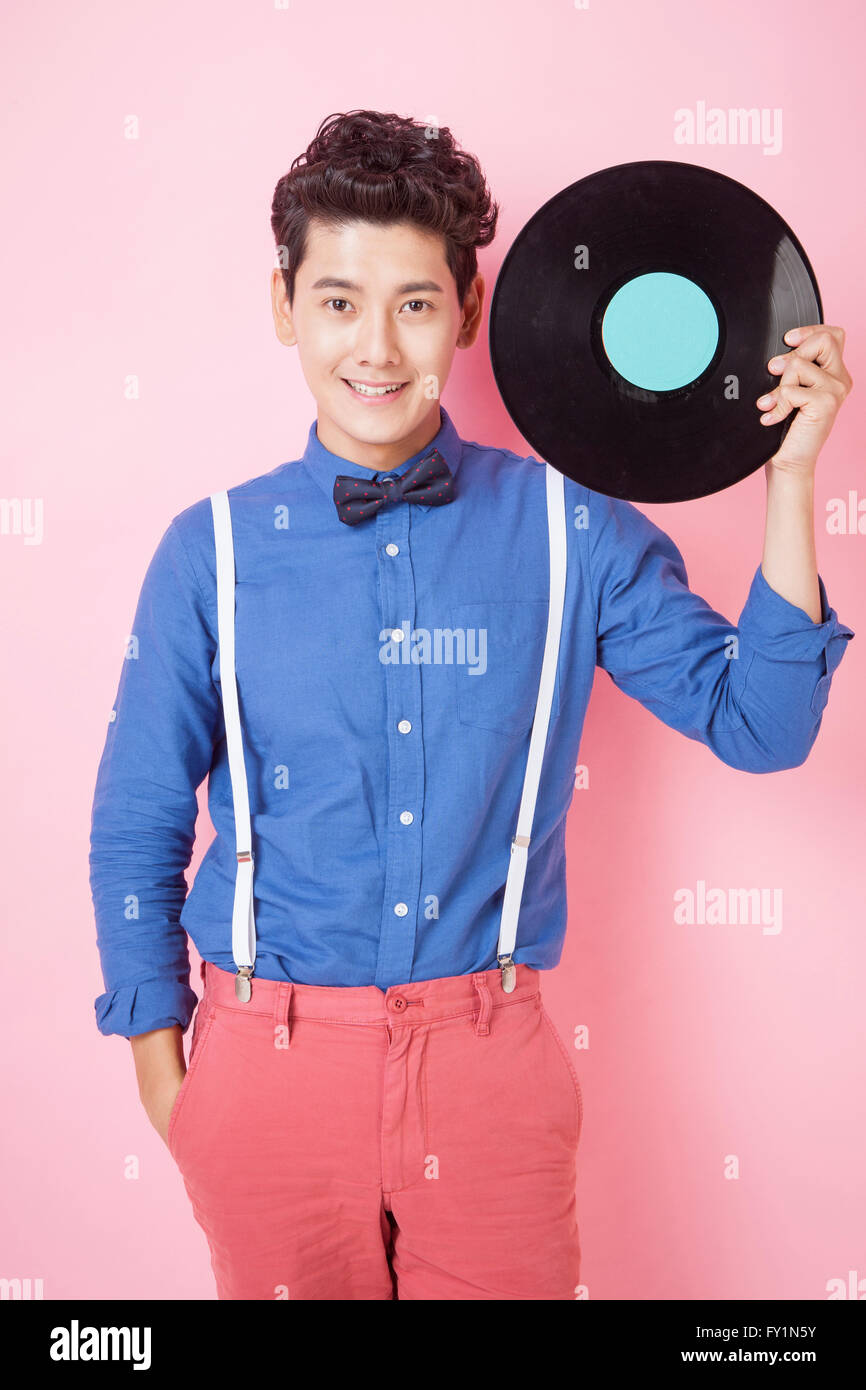 Young smiling man in retro style holding a record with one hand in his ...