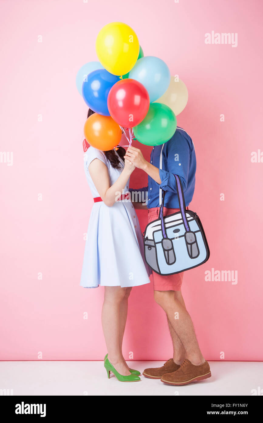 Side view of young couple in retro styles standing face ro face holding ...