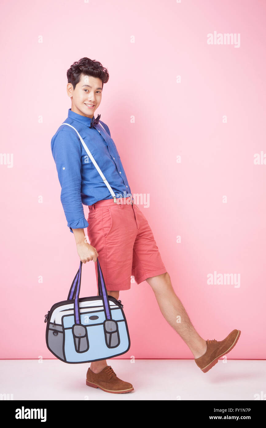 Side view of young smiling boy walking with a bag staring at front ...