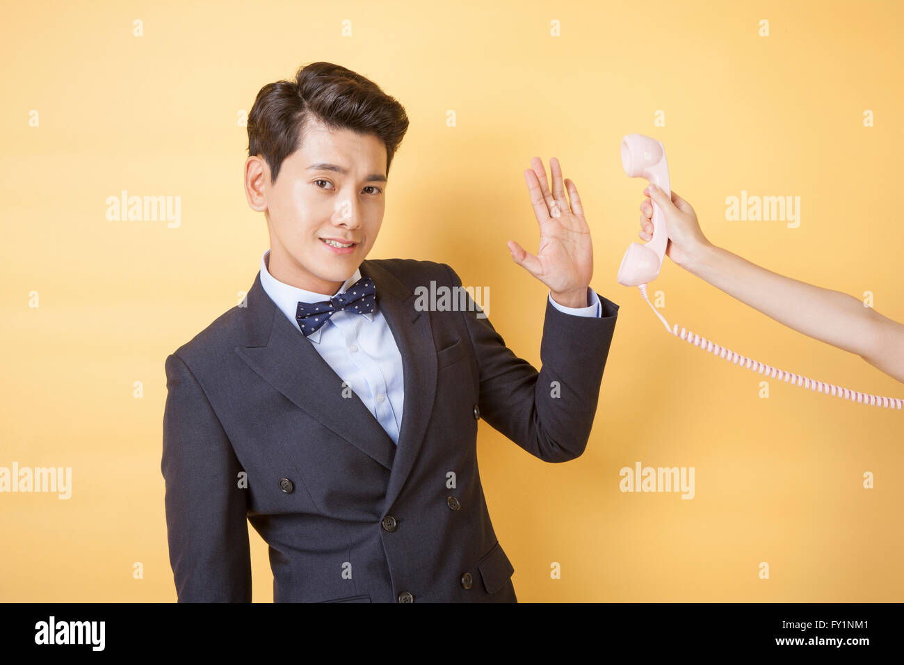 Portrait of young man in suit refusing telephone staring at front with ...
