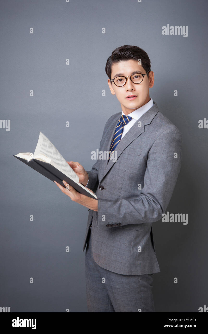 Young smiling business man in gray suit standing with an open book ...