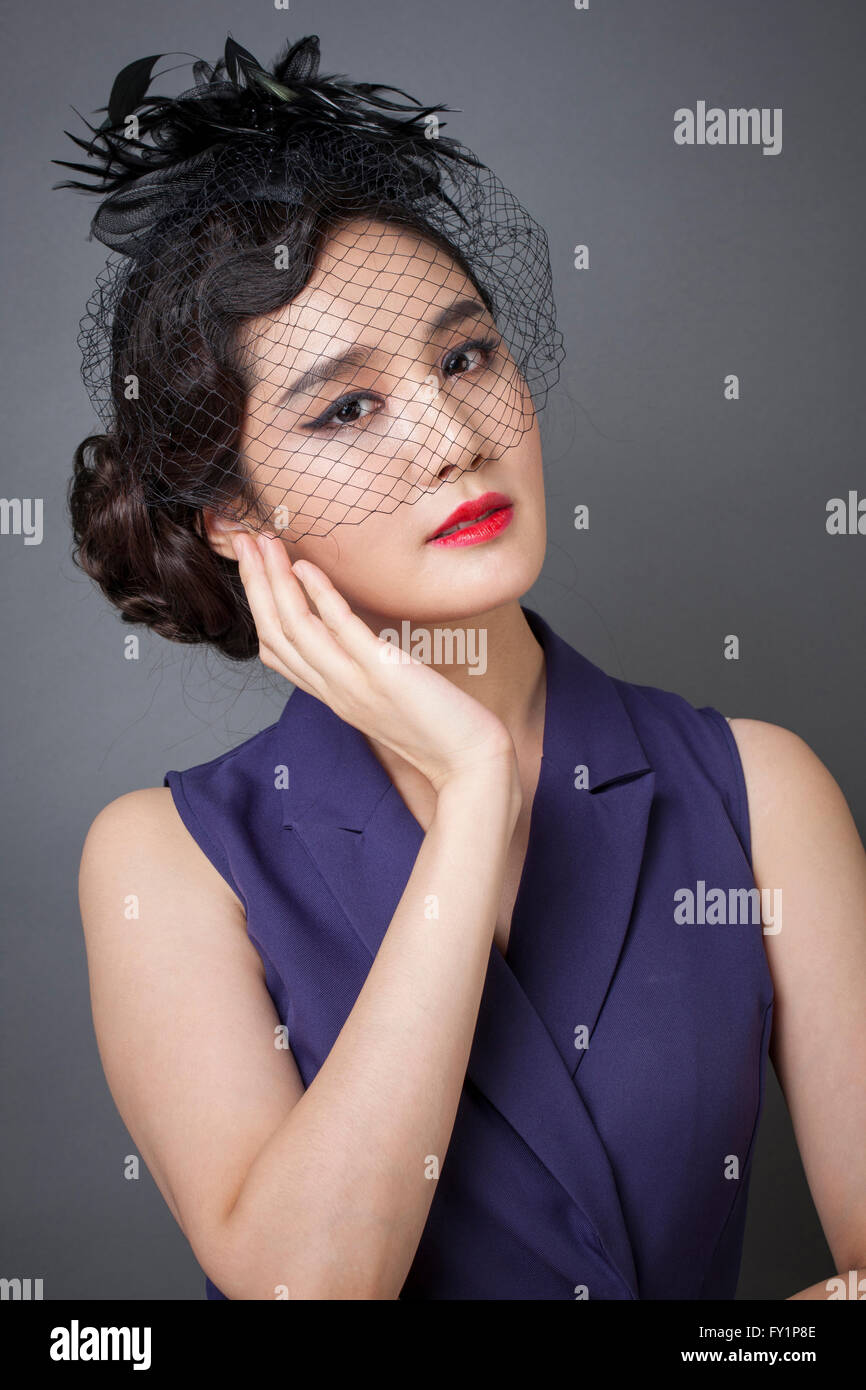 Portrait of young woman in retro style placing her face in her hand ...