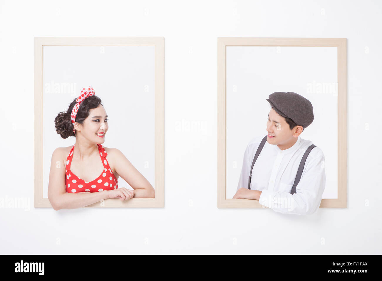 Portrait of young smiling couple in retro styles posing in a frame each ...