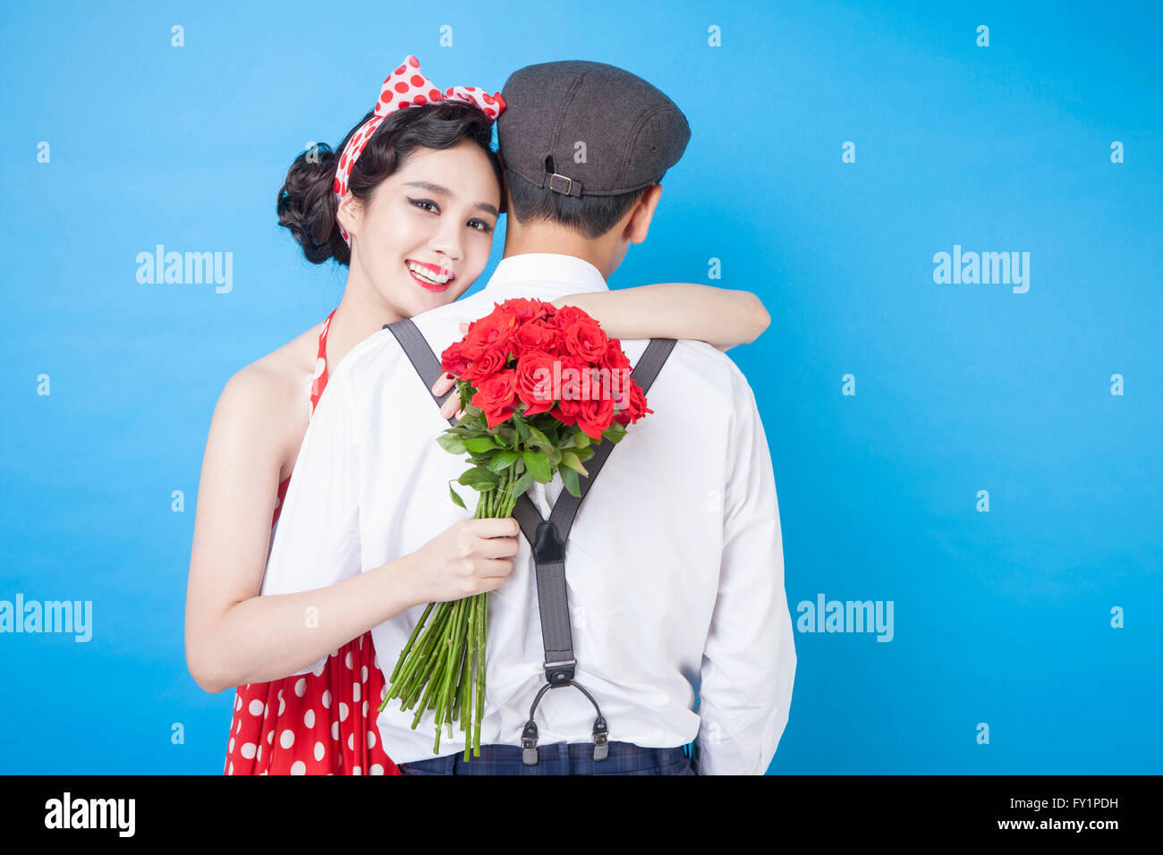 Portrait of young smiling woman with a bunch of red roses hugging a man ...