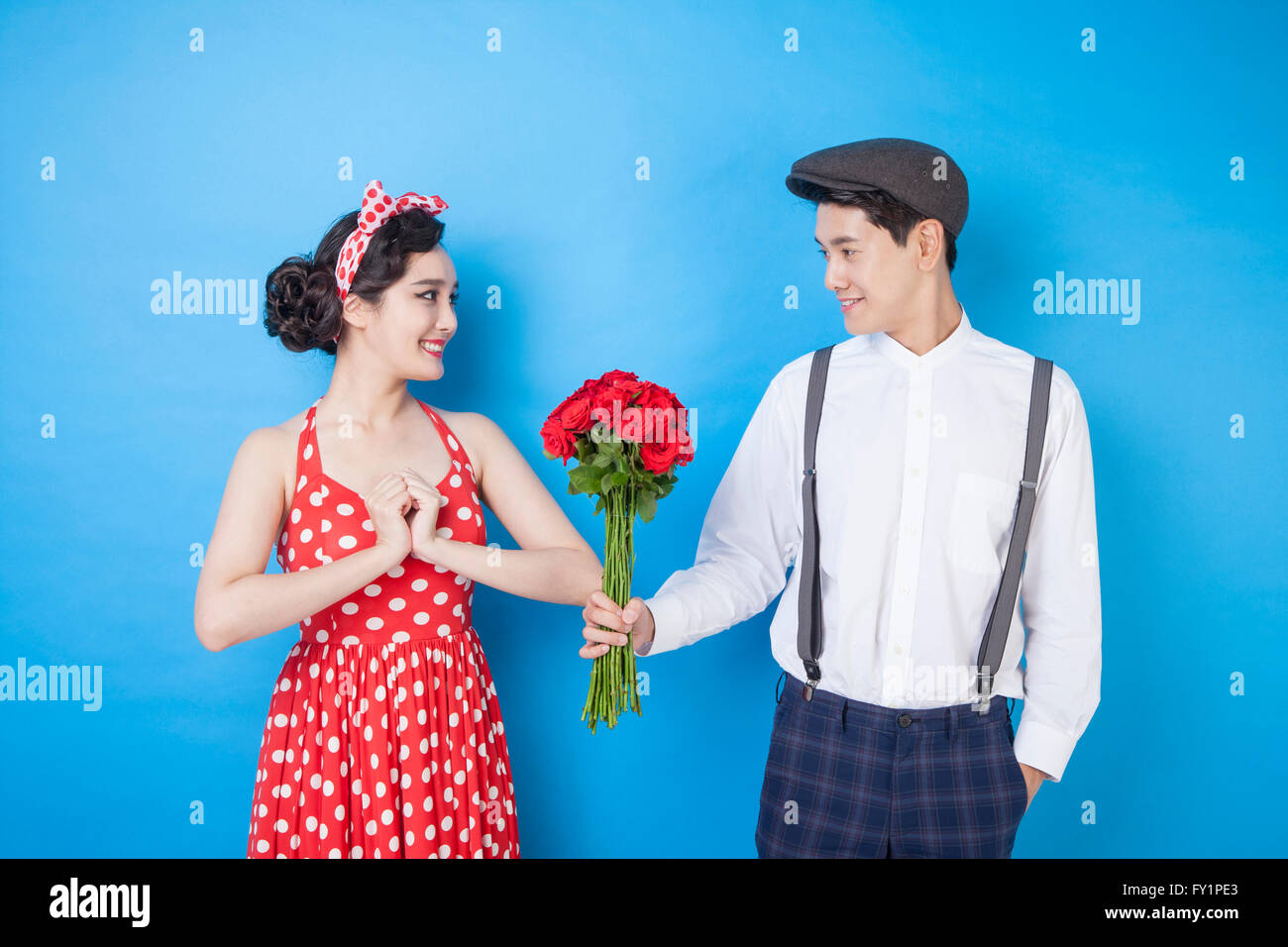 Young smiling man giving a bunch of red roses to a young smiling woman ...